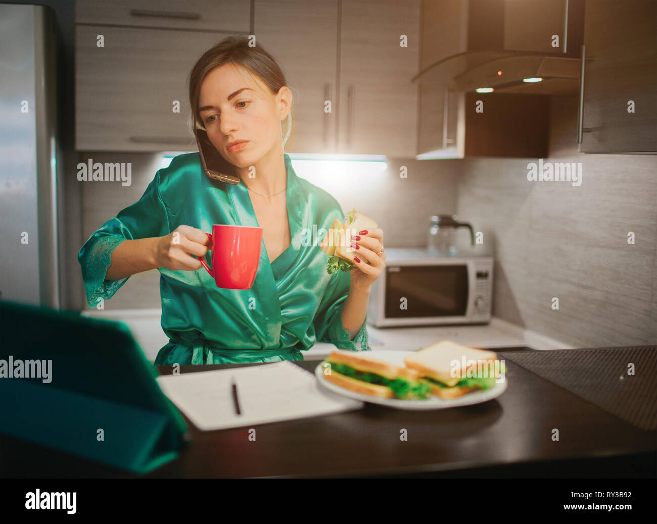 Busy woman eating, drinking coffee, talking on the phone, working on a ...