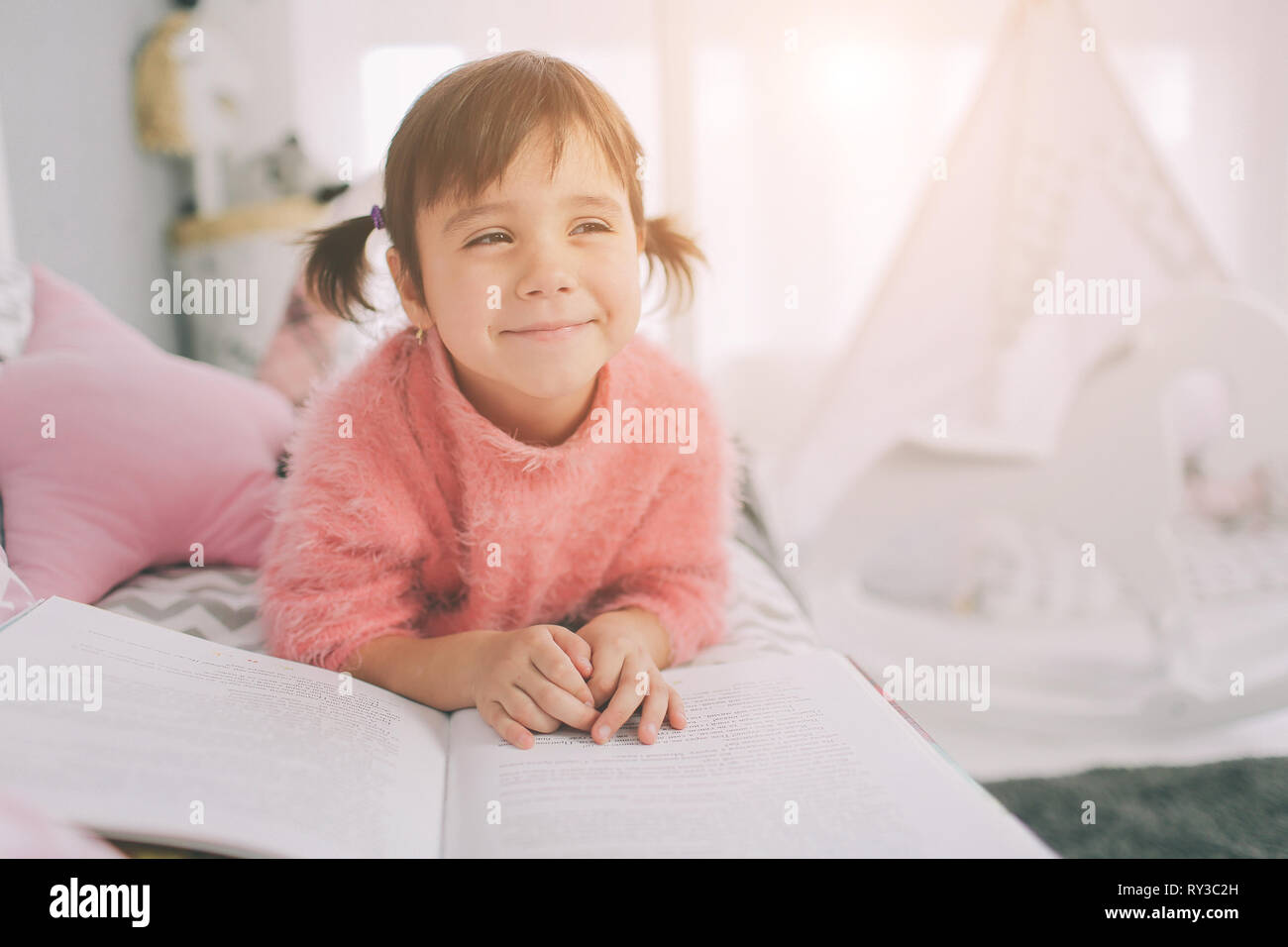Cute little kid girl is reading a book at home. Funny lovely child ...
