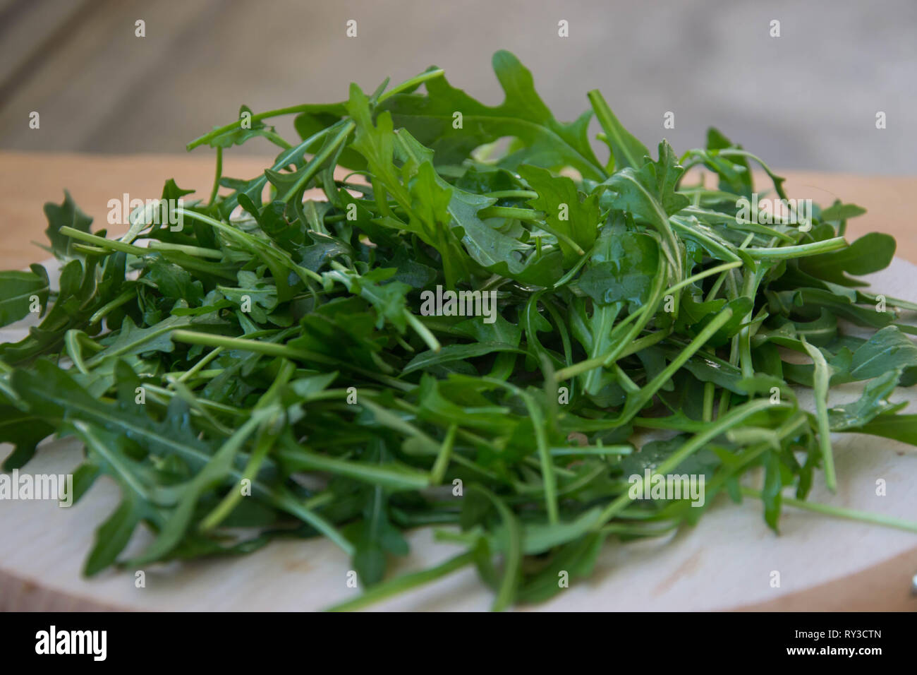 Green arugula leaves on wooden cutting board. Fresh rucola in the ...