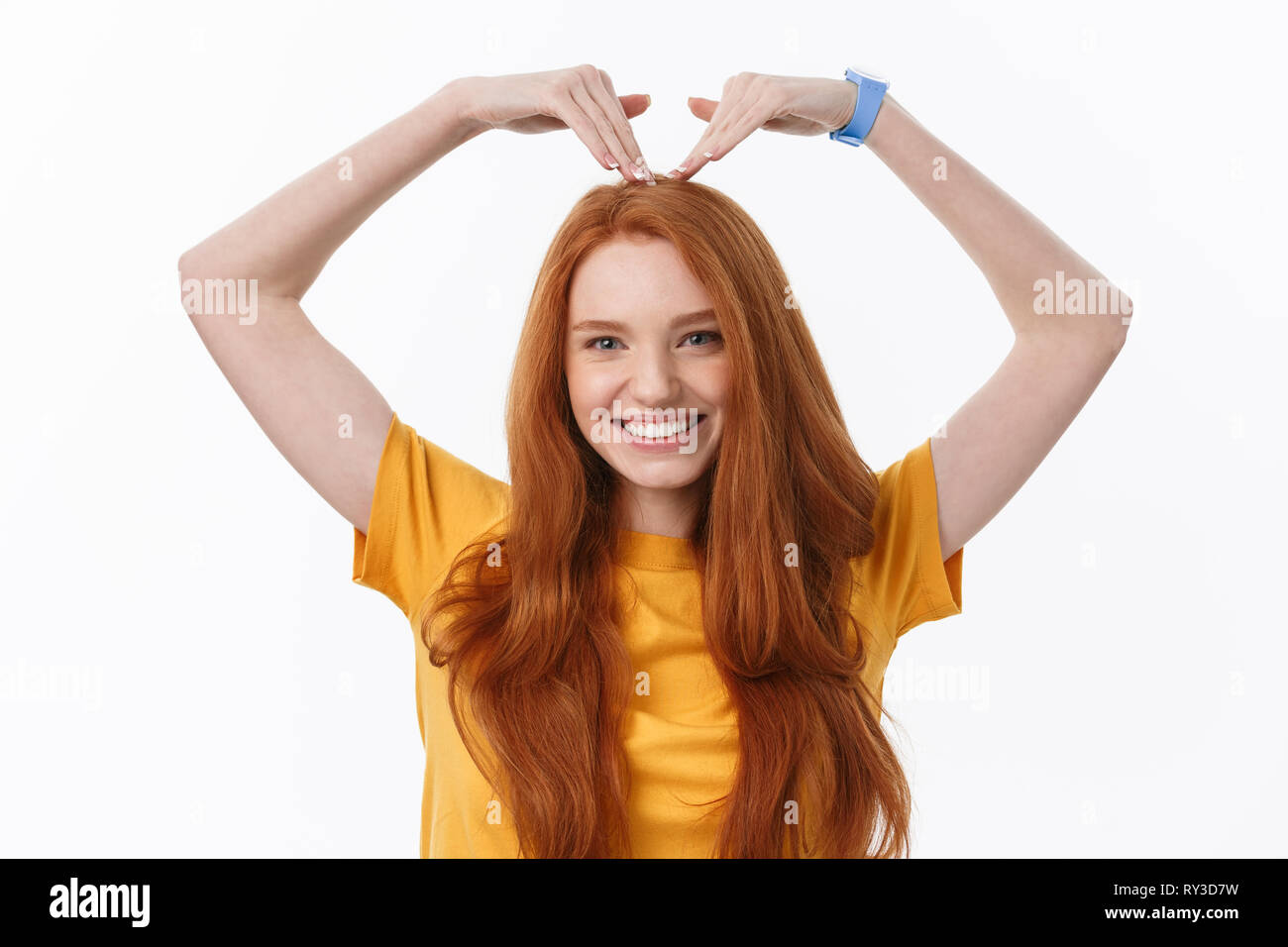 Pretty romantic young redhead woman making a heart gesture with a happy ...