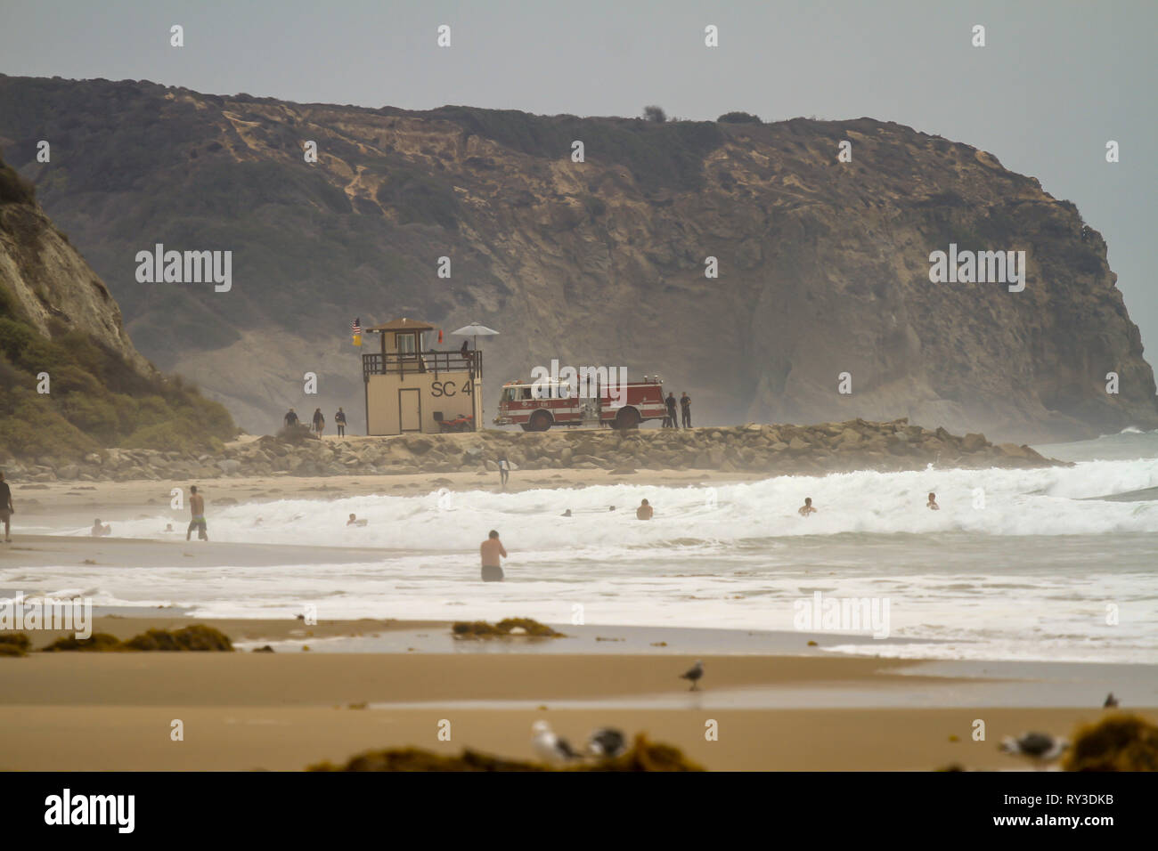 People swimming in rough seas amongst the breaking waves below a high ...