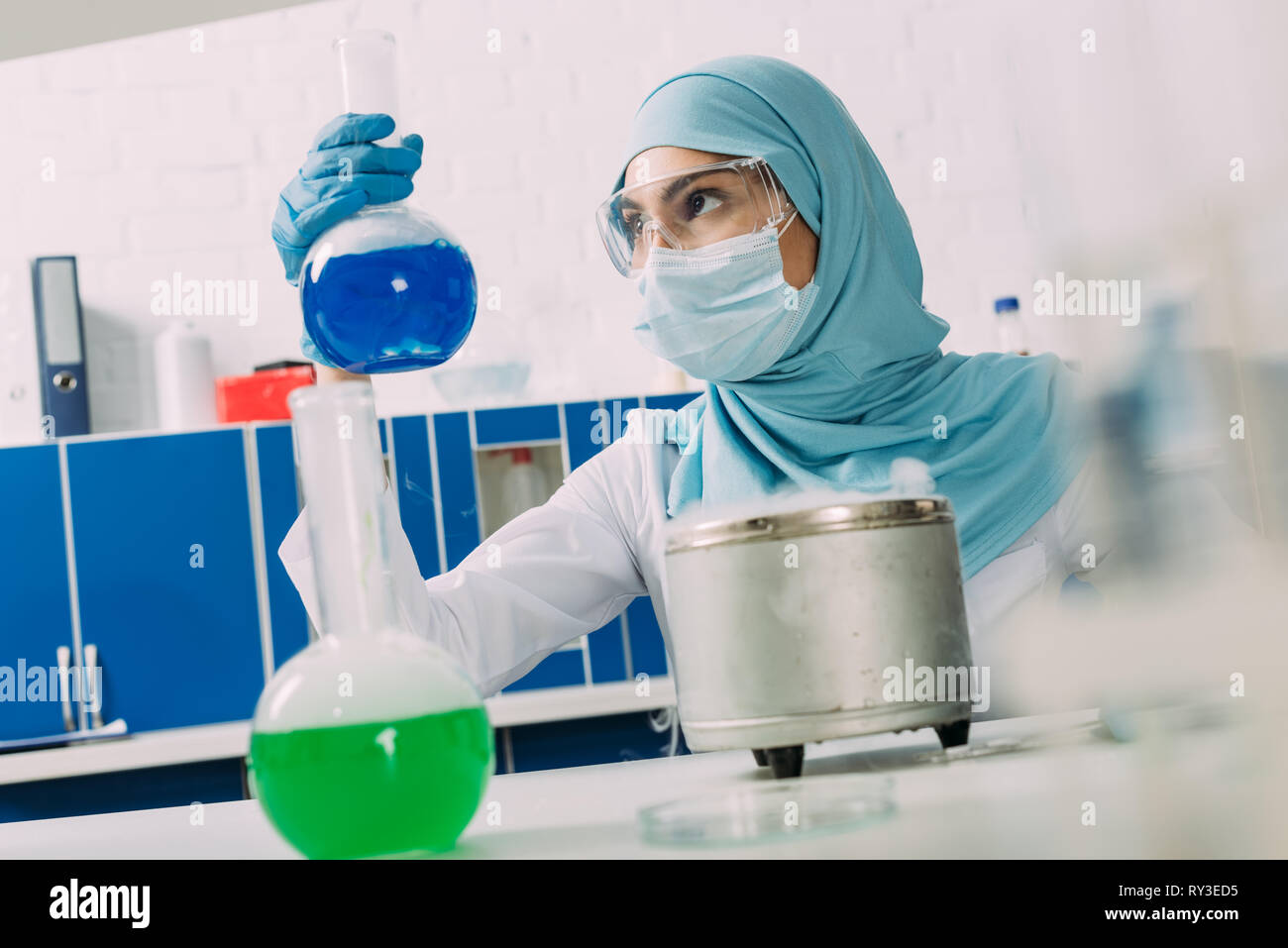 female muslim scientist looking at flask during experiment in chemical laboratory Stock Photo ...