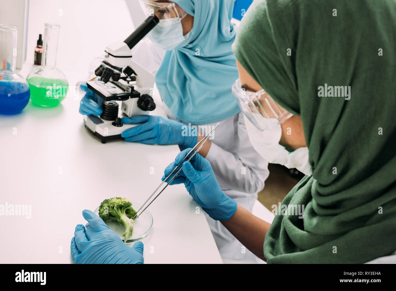 female muslim scientists looking through microscope and taking sample ...