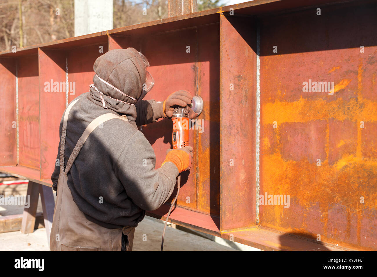 An employee in white overalls and a protective mask processes with ...