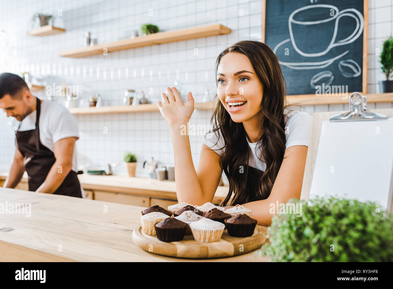 selective focus of attractive brunette waitress standing behind bar ...