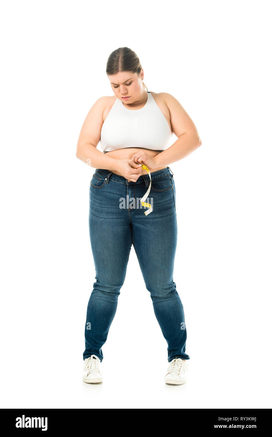upset overweight woman in jeans measuring waist with measuring tape ...