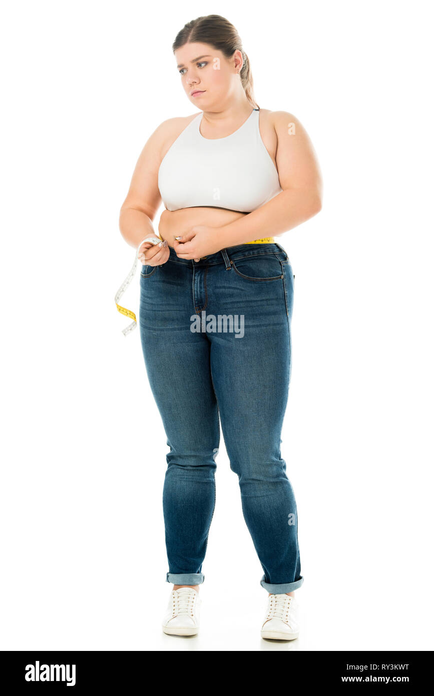 dissatisfied overweight woman in jeans measuring waist with measuring ...