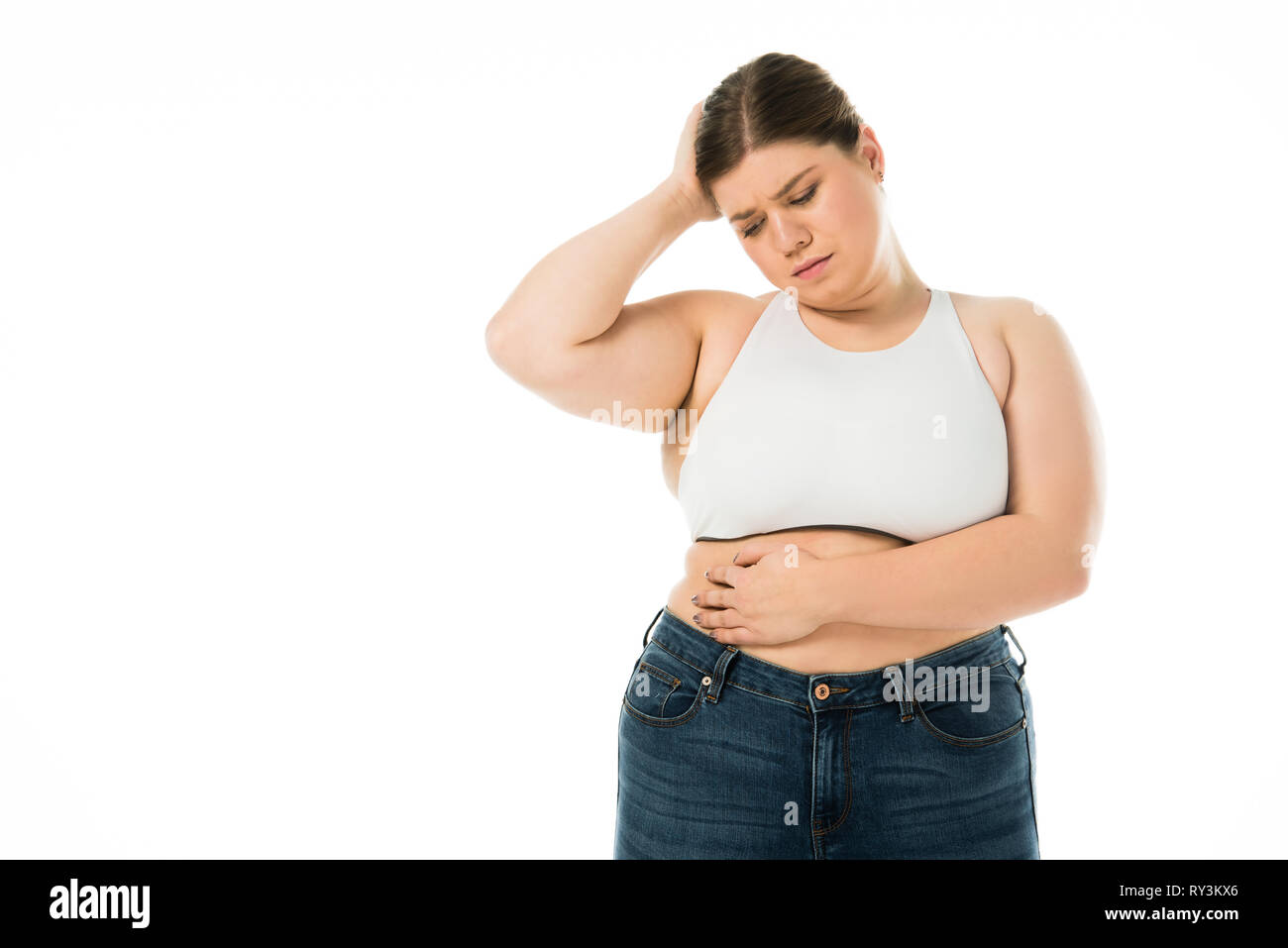 sad overweight woman in denim touching belly isolated on white Stock ...