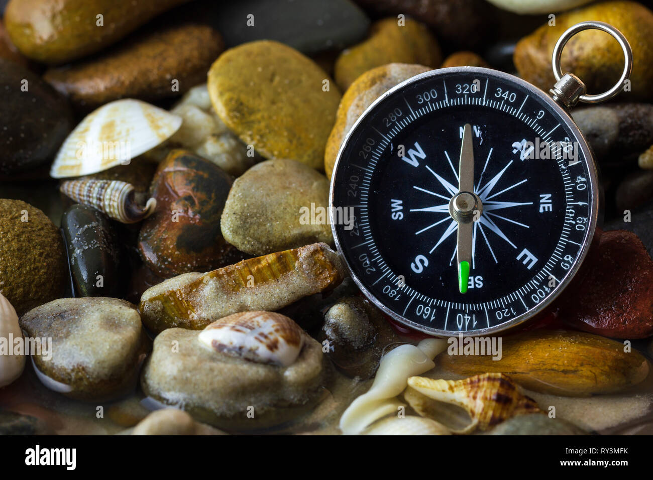 Compass on the pebbles and shell at riverside. Concepts of tourism and ...