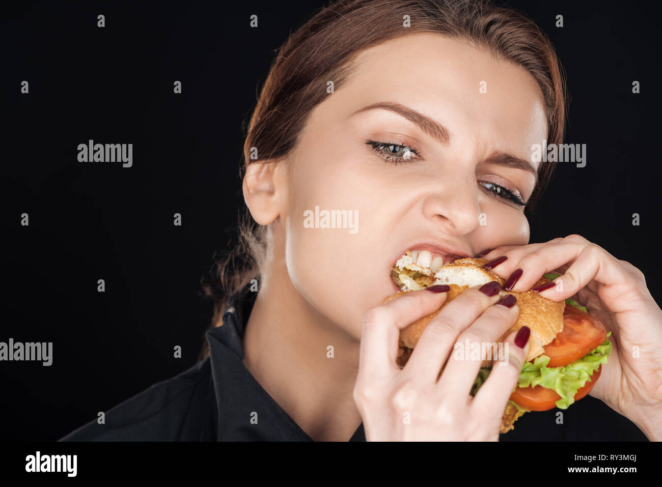 angry woman eating tasty chicken burger isolated on black Stock Photo ...