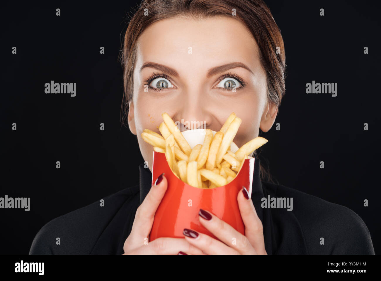 shocked woman covering face with french fries isolated on black Stock ...