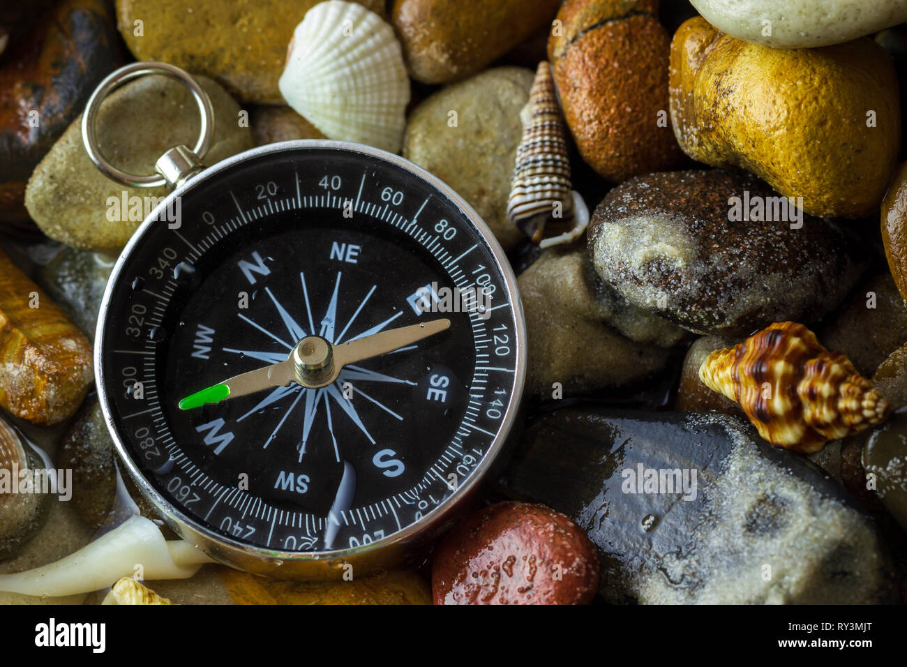 Compass on the pebbles and shell at riverside. Concepts of tourism and ...