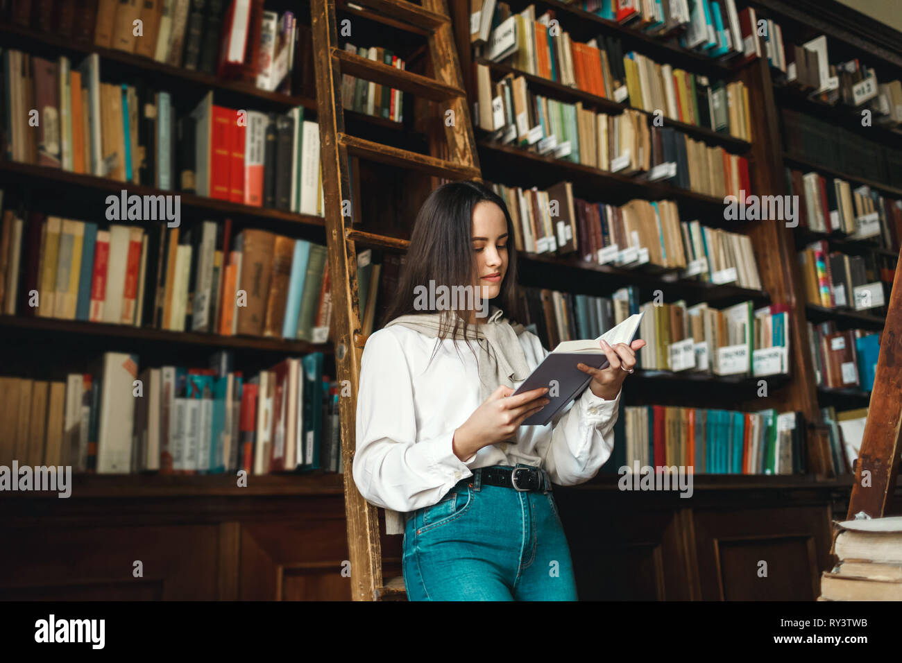 Portrait of college girl reading book in library Stock Photo - Alamy