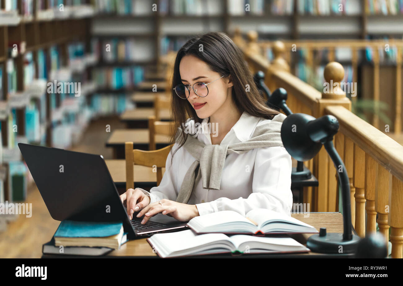 Pretty female student with laptop and books working in a high school ...