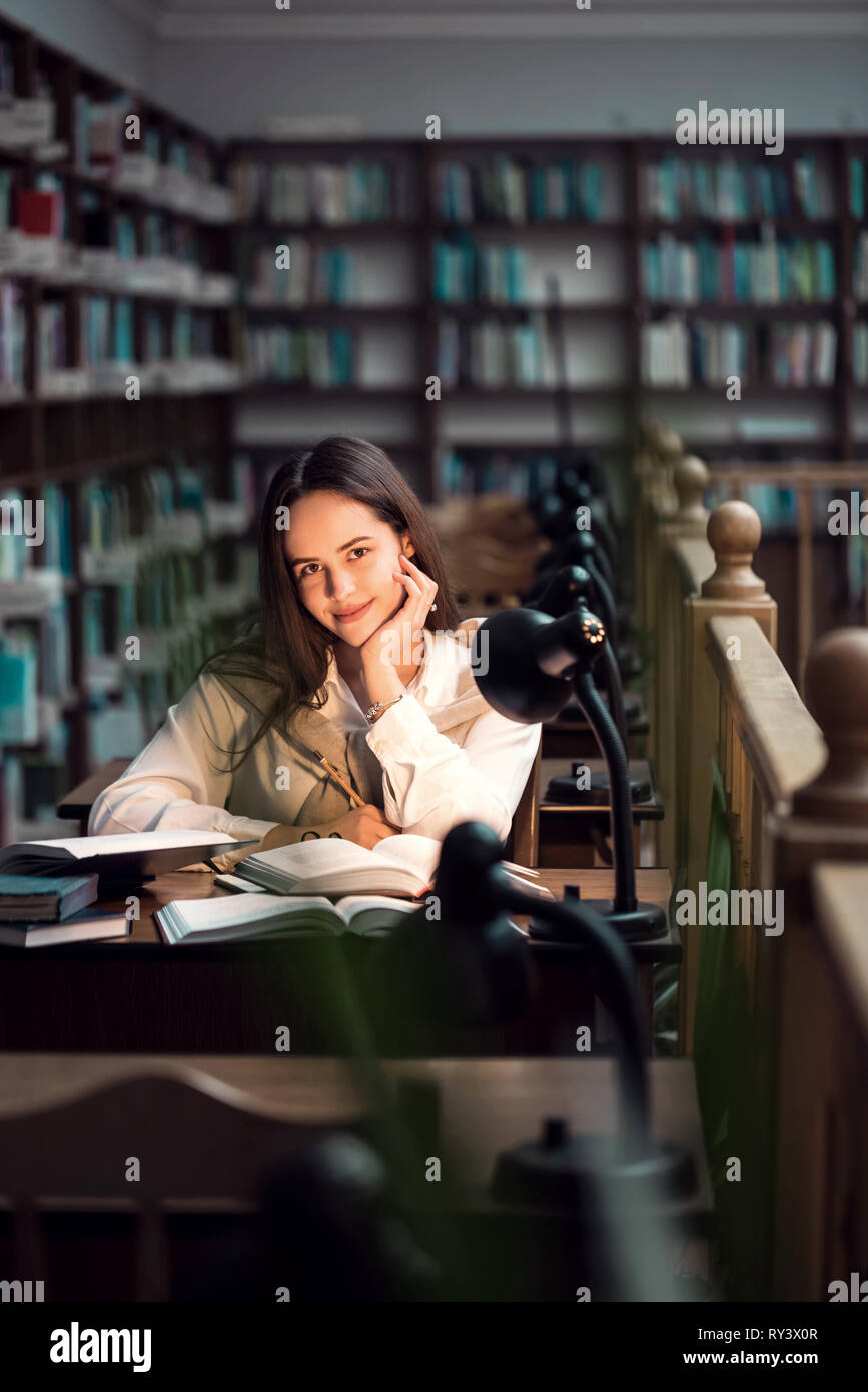 Brunette university girl taking notes from textbooks Stock Photo - Alamy