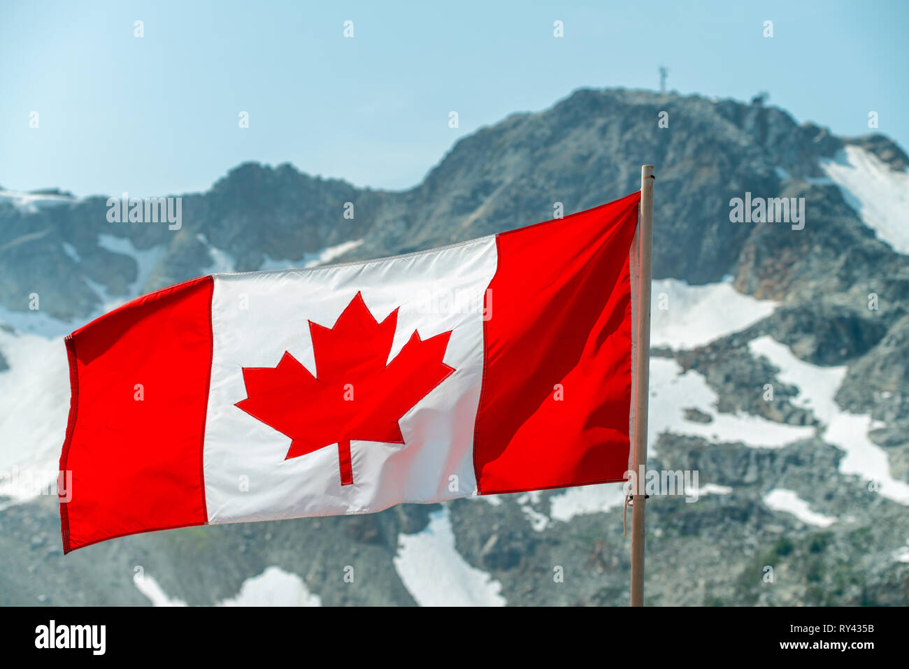 Beautiful Canadian Flag waving for the strong wind, tall mountains in ...