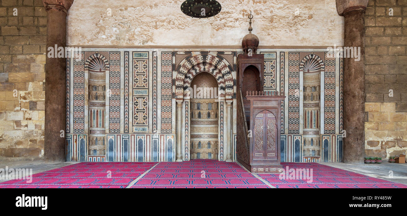 Colorful decorated marble wall with engraved Mihrab (niche) and wooden ...