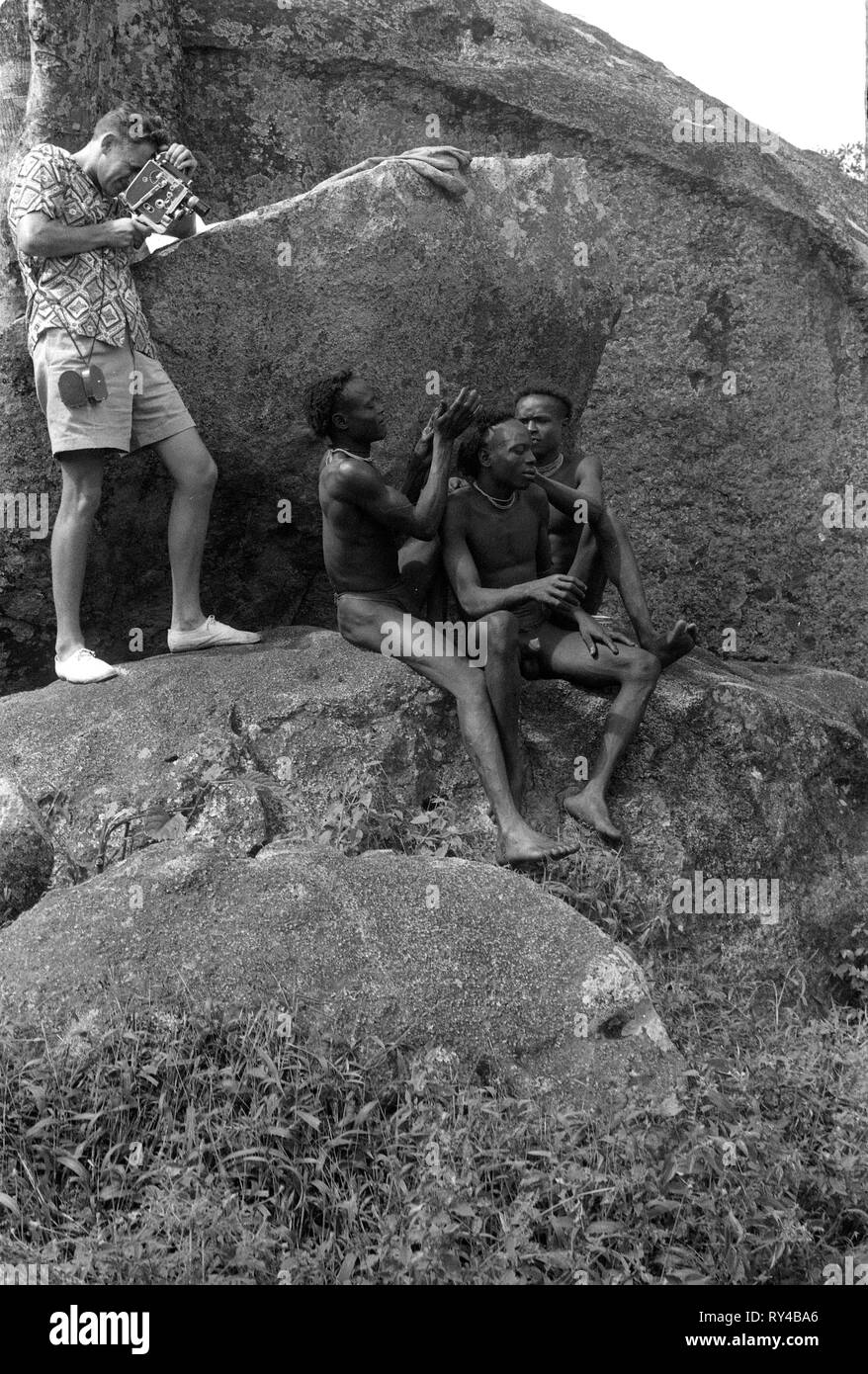 Western cameraman filming African native tribesmen performing a ...