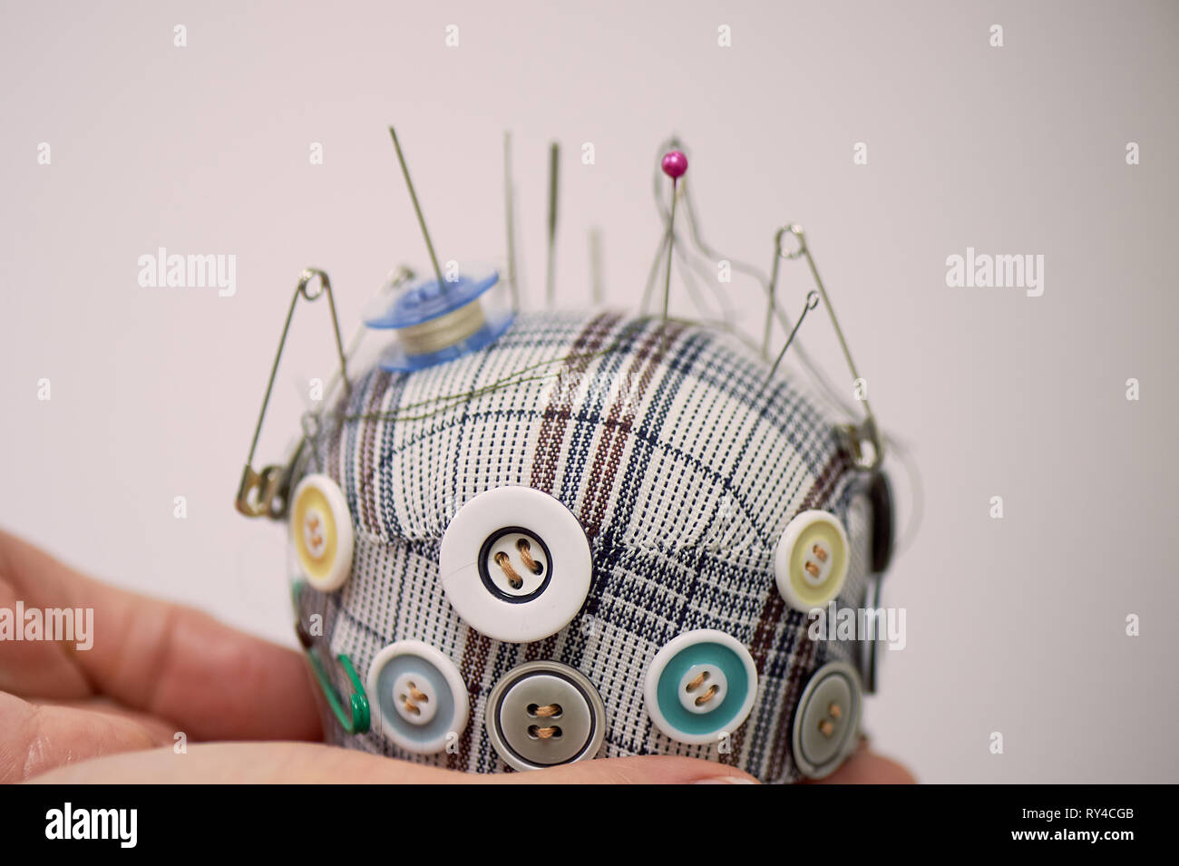 Plaid pin cushion in the hands of seamstresses.Handmade, sewing Stock ...