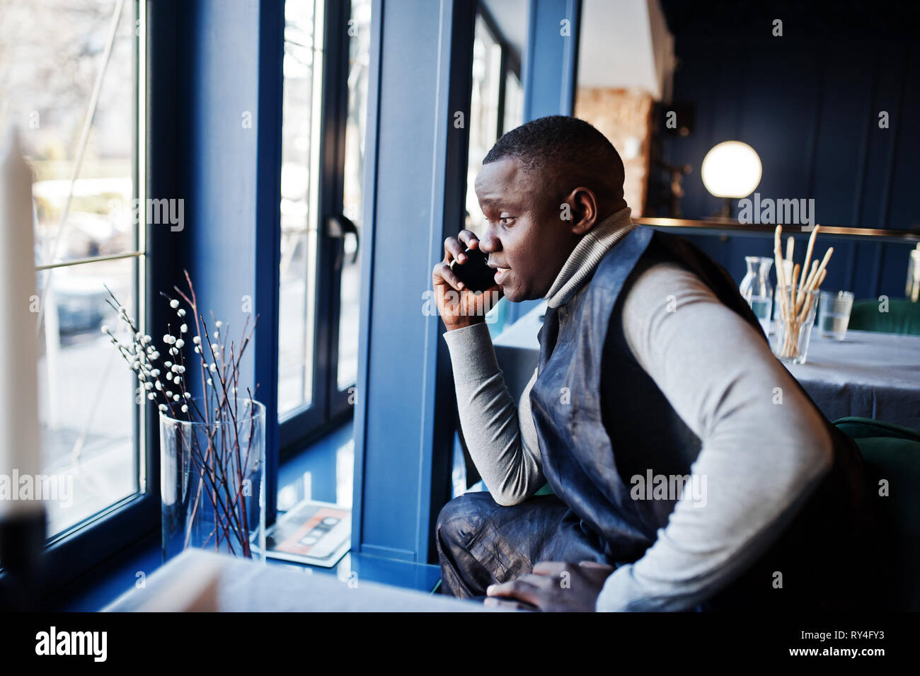 African man in black traditional clothes sitting at restaurant and ...