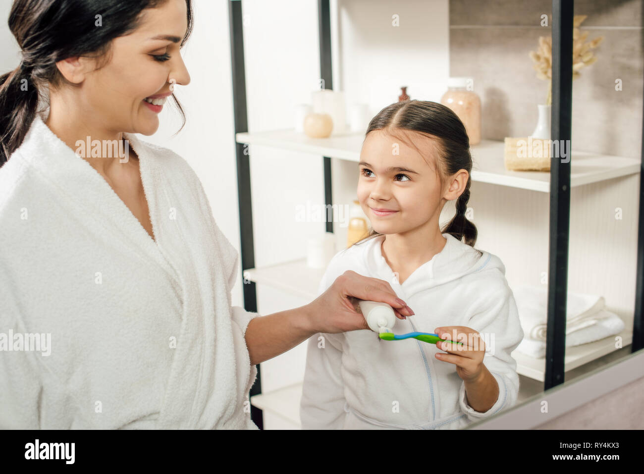 mother applying toothpaste on daughter toothbrush in bathroom Stock ...