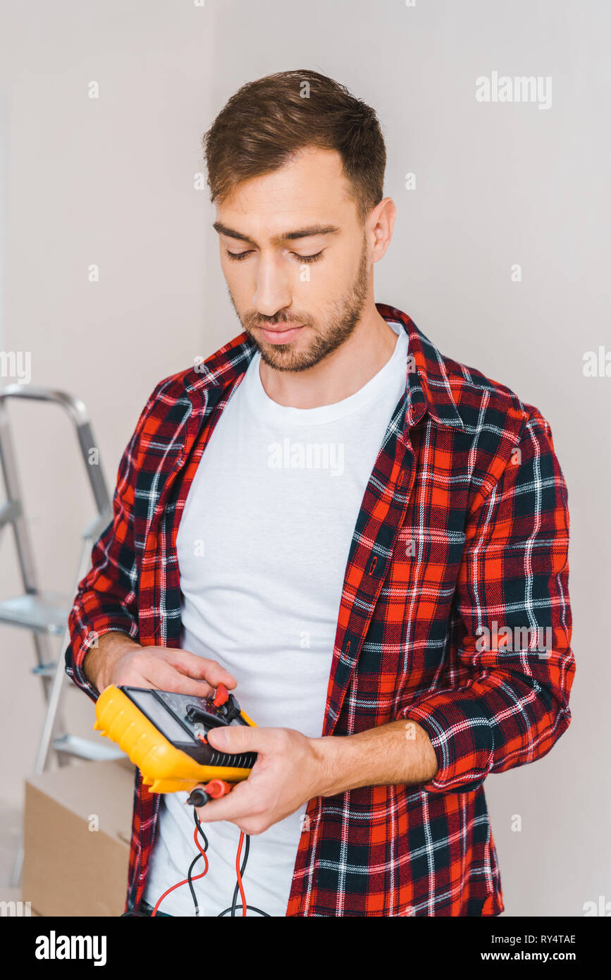 handsome man holding digital multimeter at home Stock Photo - Alamy