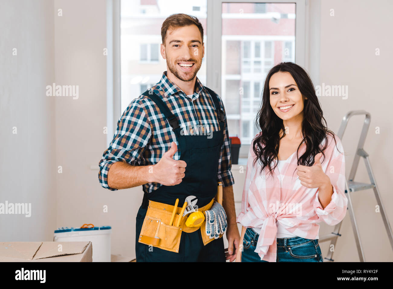 attractive woman and handsome handyman showing thumbs up Stock Photo ...