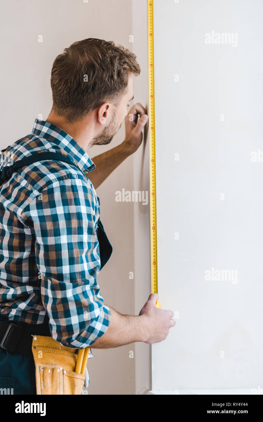 handyman standing and measuring wall with measuring tape Stock Photo ...