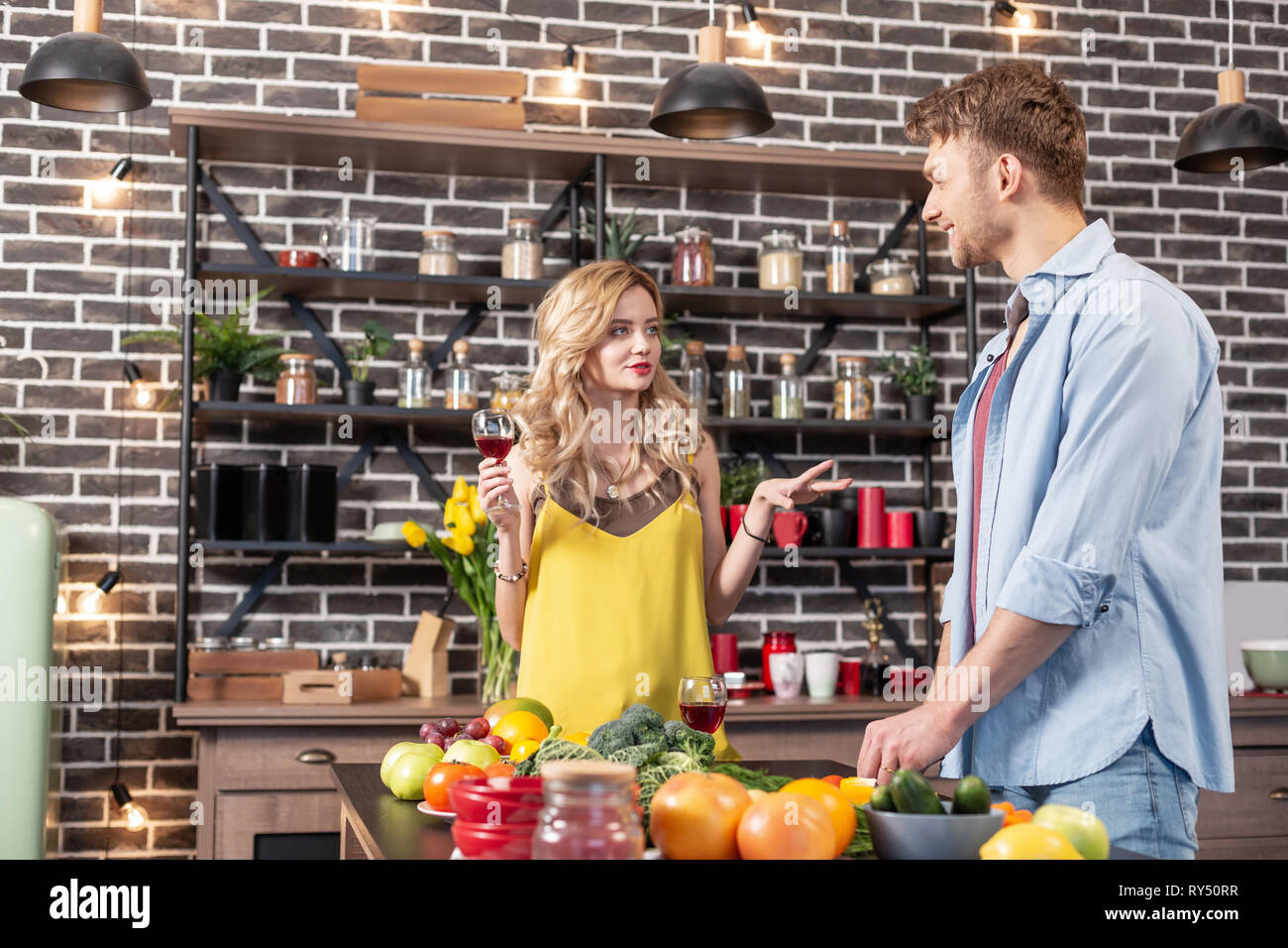 Bearded husband cooking salad and talking to his appealing beloved ...