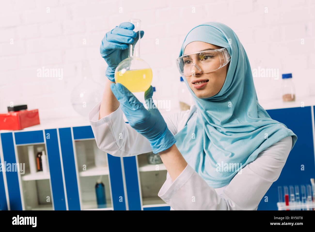 female muslim scientist holding flask during experiment in chemical ...