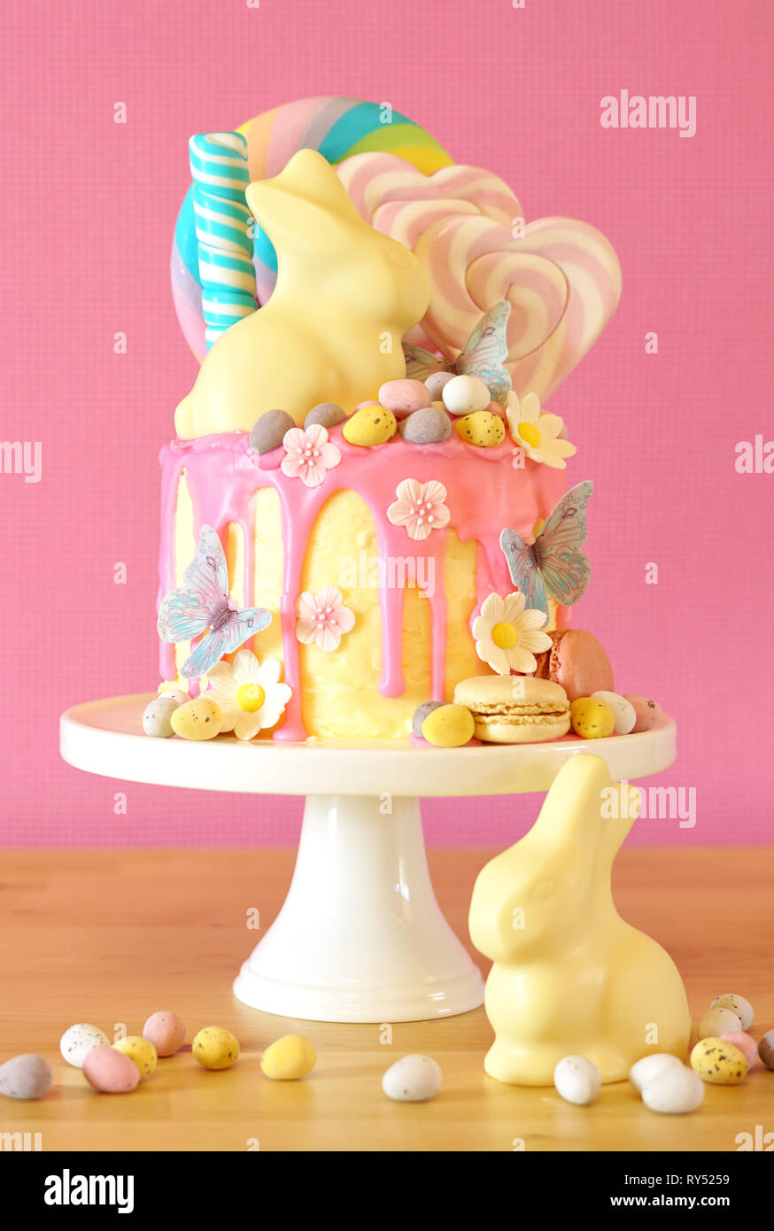 On-trend Easter theme candy land drip cake decorated with lollipops, candy eggs and white ...