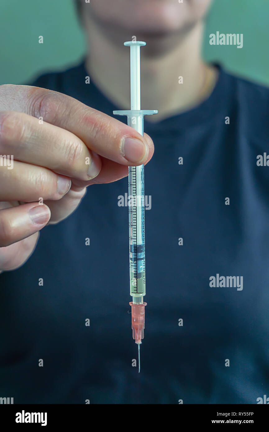 young drug addict with a syringe in her hand makes herself an injection ...