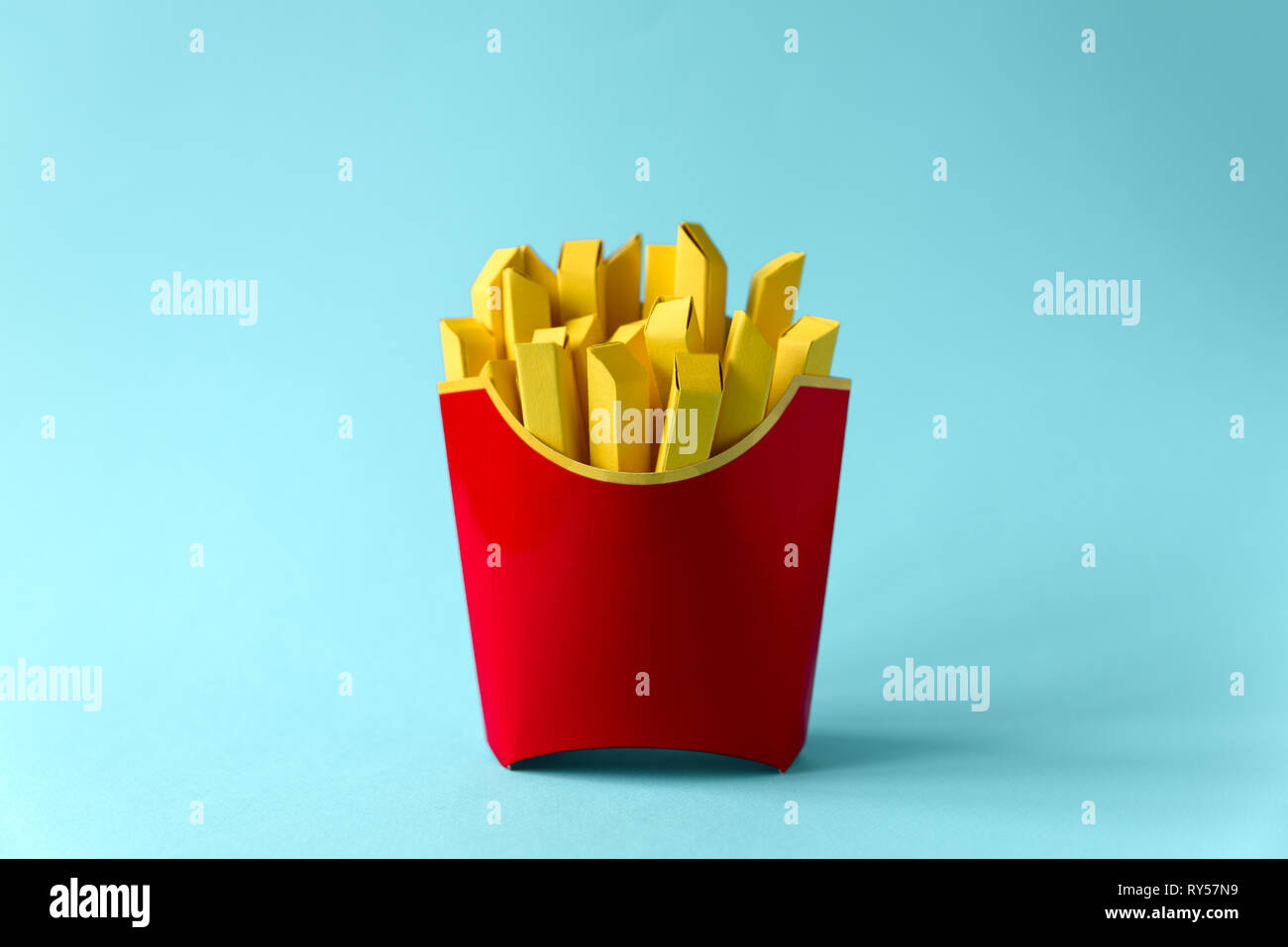 Paper French fries in red carton box on blue background. Copy space ...