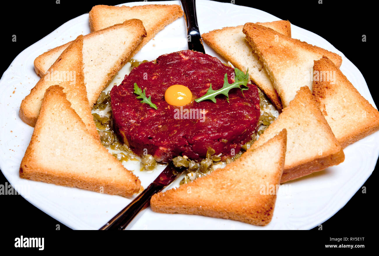 Fried tartar meat dish with yolk and a crown on a black wooden ...