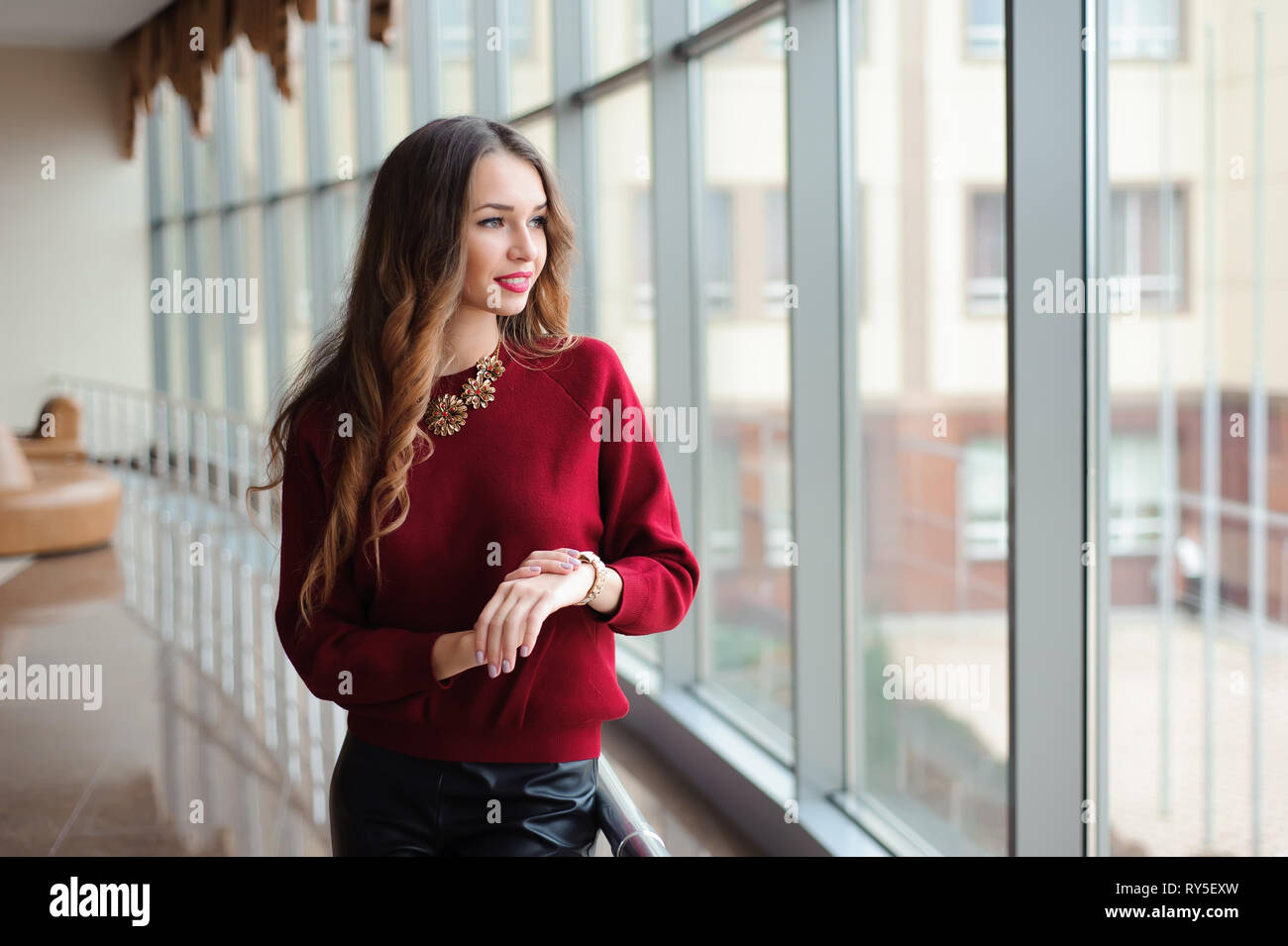 beautiful woman looks at the clock waiting for the plane at the airport ...