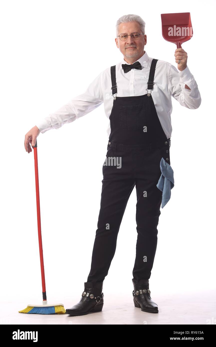 Gray-haired cleaner, janitor in a black jumpsuit with a mop and dustpan ...