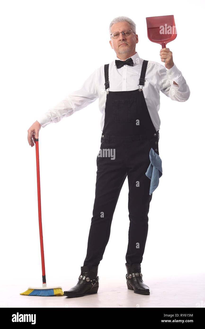 Gray-haired cleaner, janitor in a black jumpsuit with a mop and dustpan ...