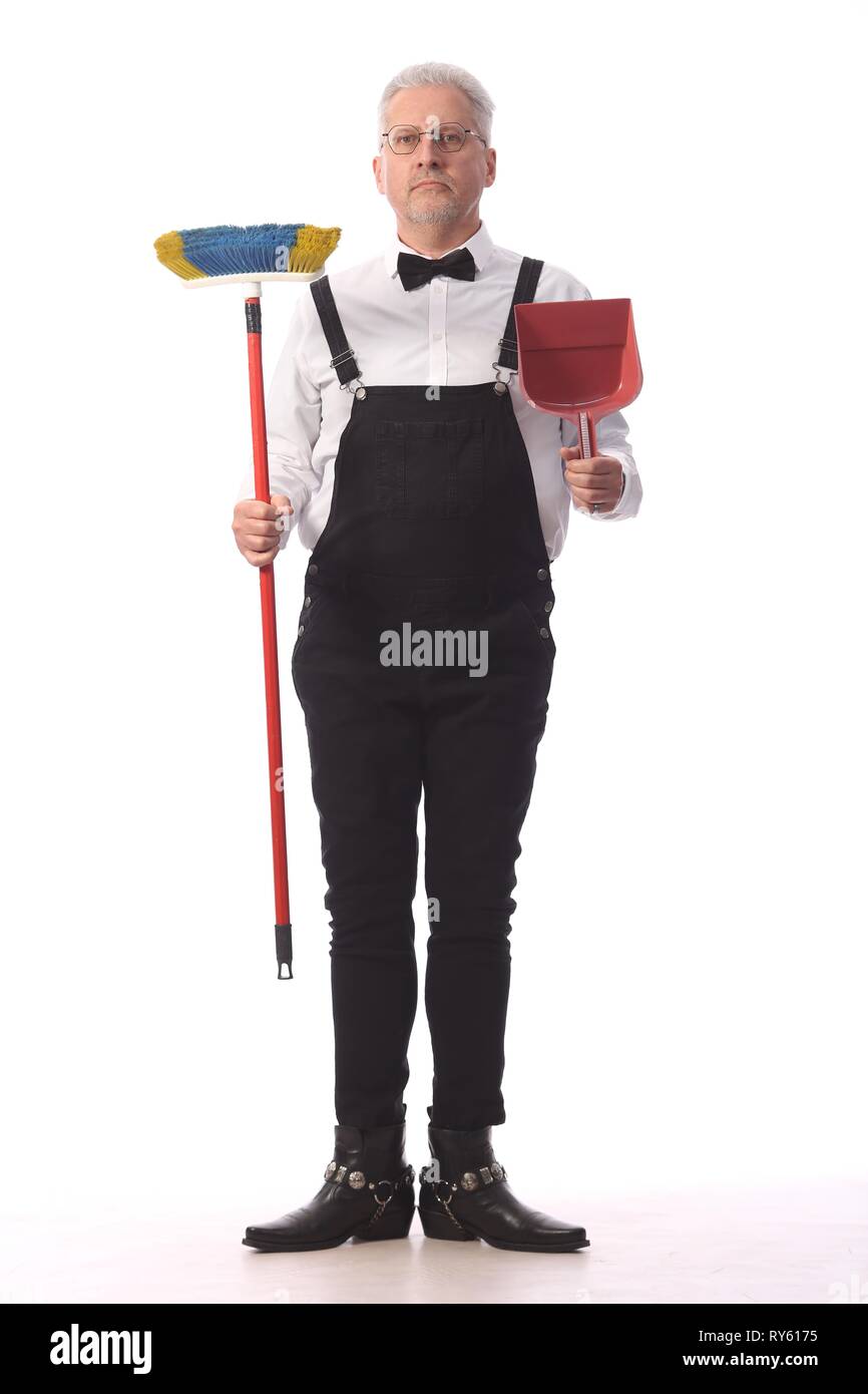 Gray-haired cleaner, janitor in a black jumpsuit with a mop and dustpan ...