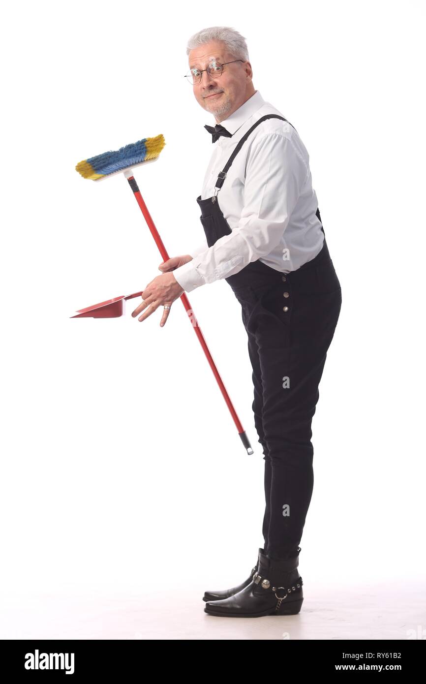 Gray-haired cleaner, janitor in a black jumpsuit with a mop and dustpan ...