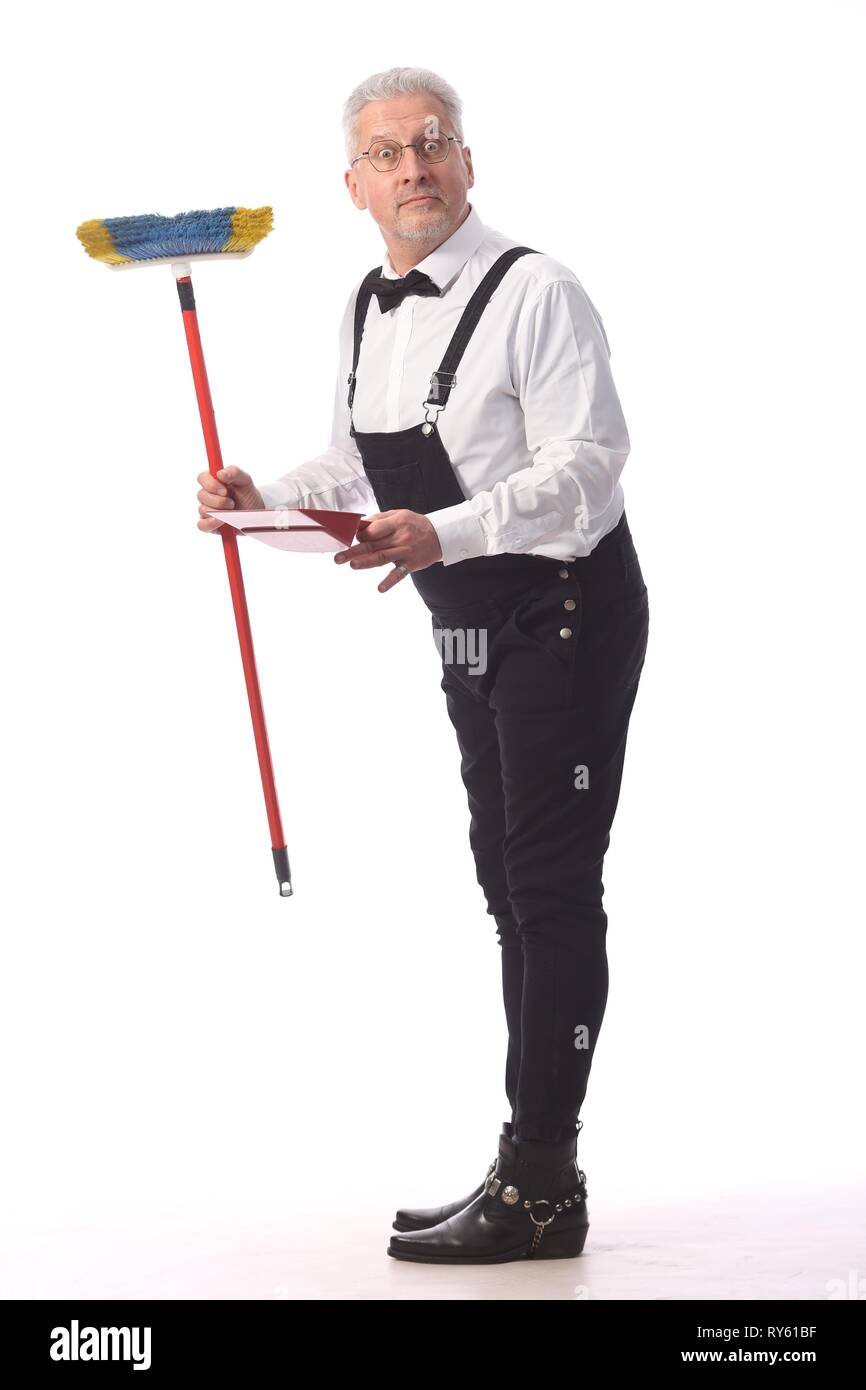 Gray-haired cleaner, janitor in a black jumpsuit with a mop and dustpan ...