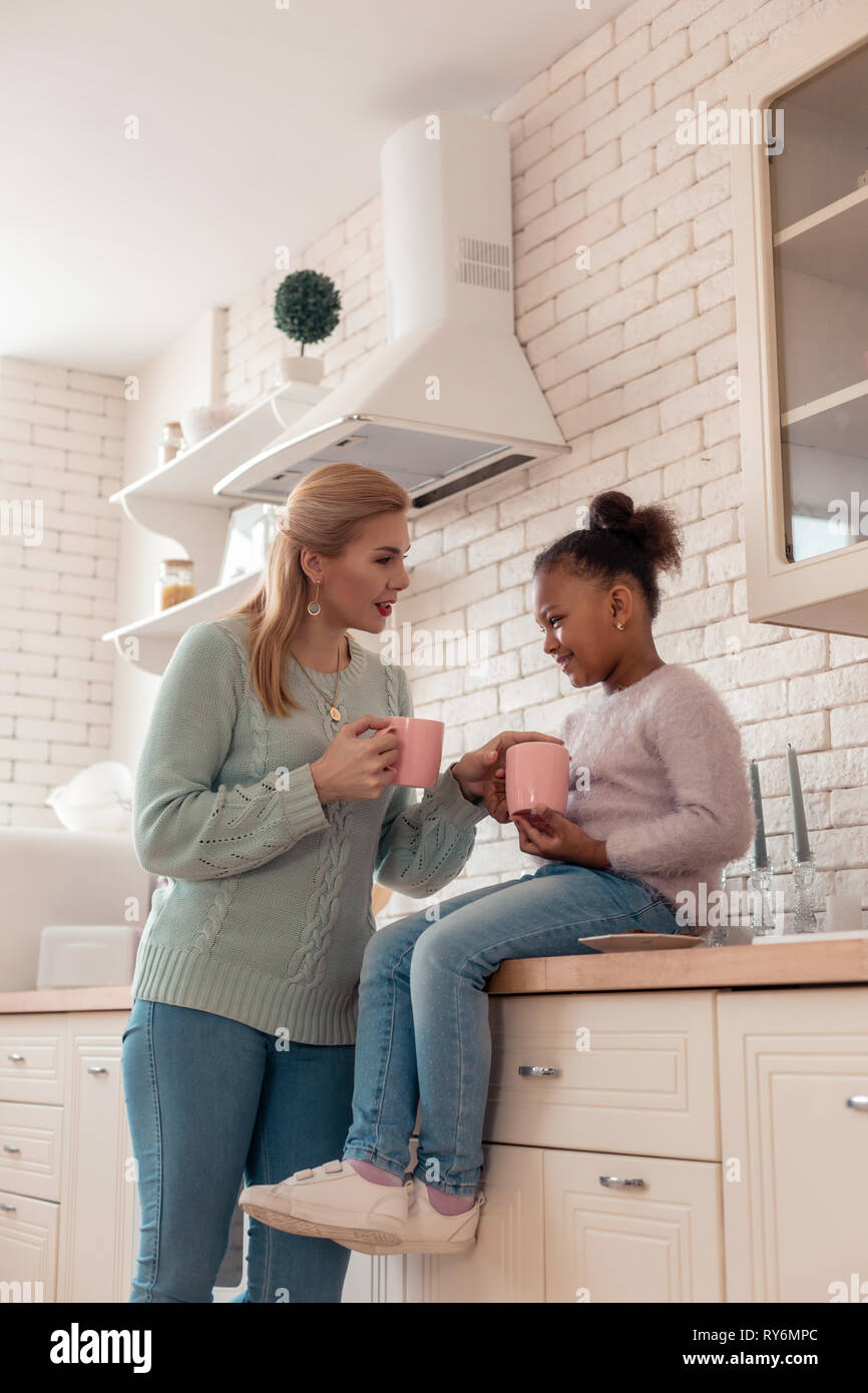 Blonde-haired mother drinking tea with daughter before work Stock Photo ...