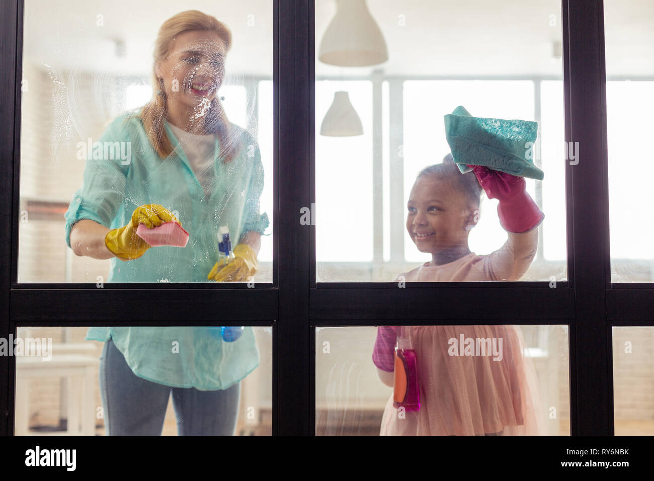 Mother and daughter spending time together while cleaning the flat ...