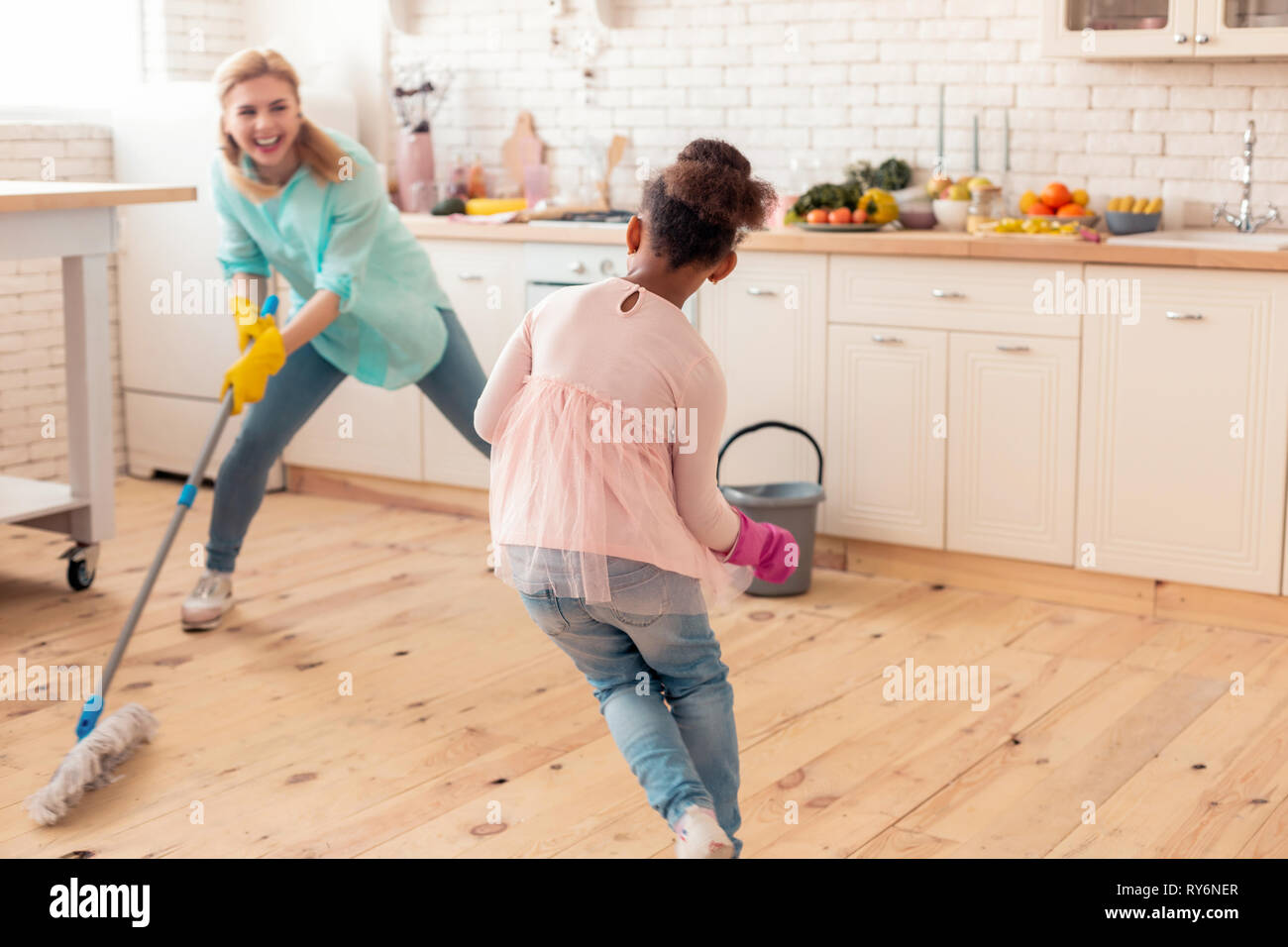 Mother And Daughter Playing Hide And Seek While Cleaning The Kitchen