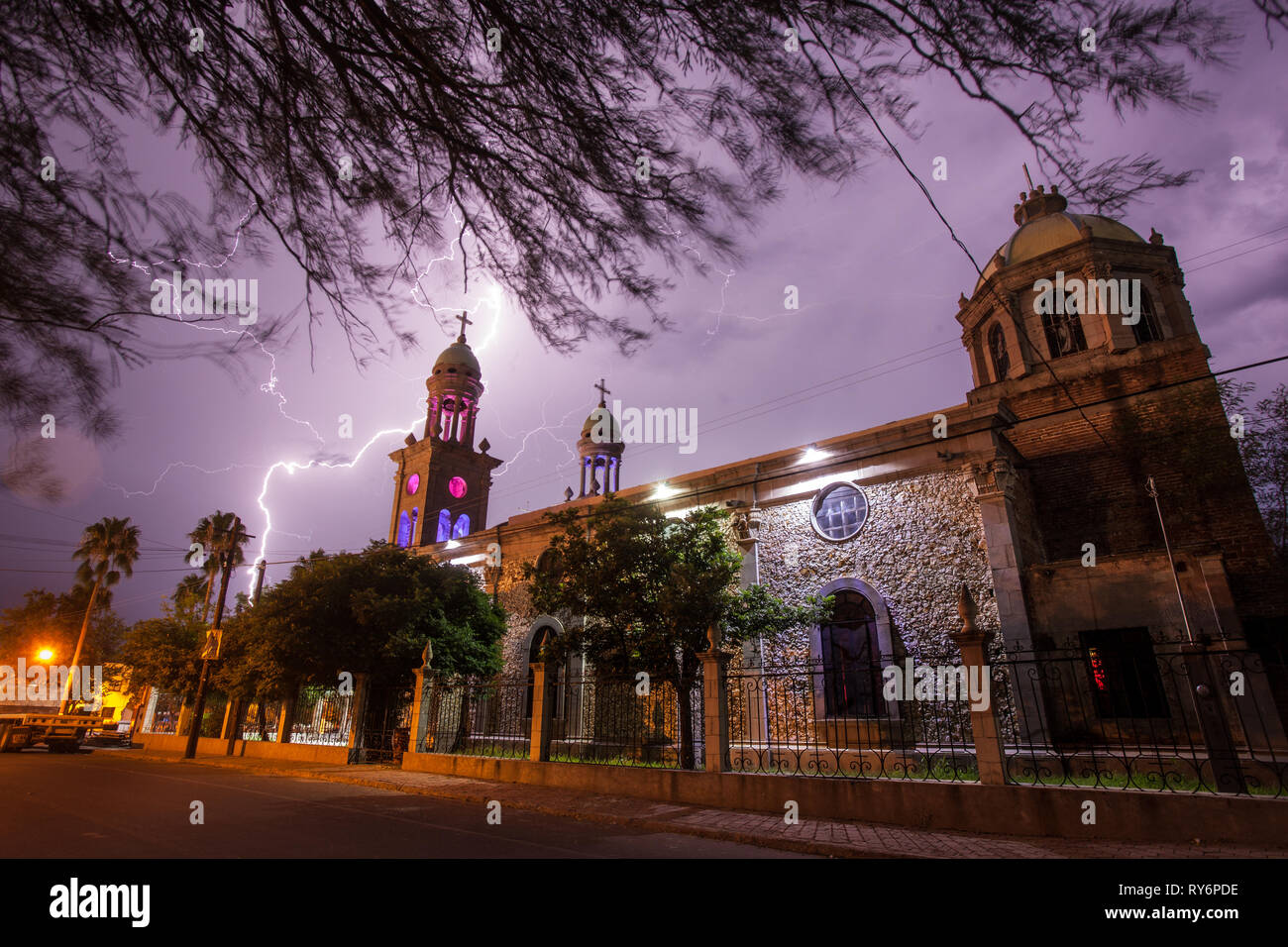 Lightning strikes behind a historic mission church on a plaza in the ...