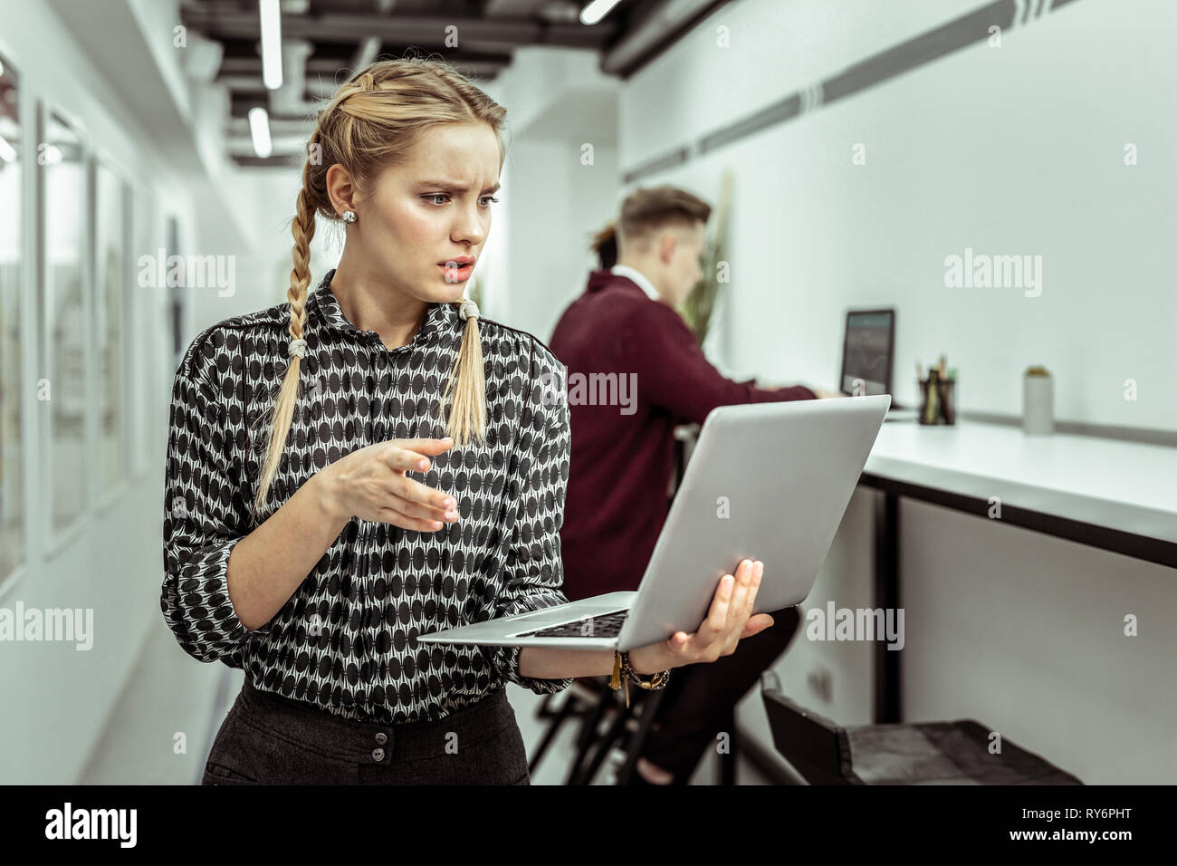 Confused woman with two braids looking nonplussed while dealing with ...
