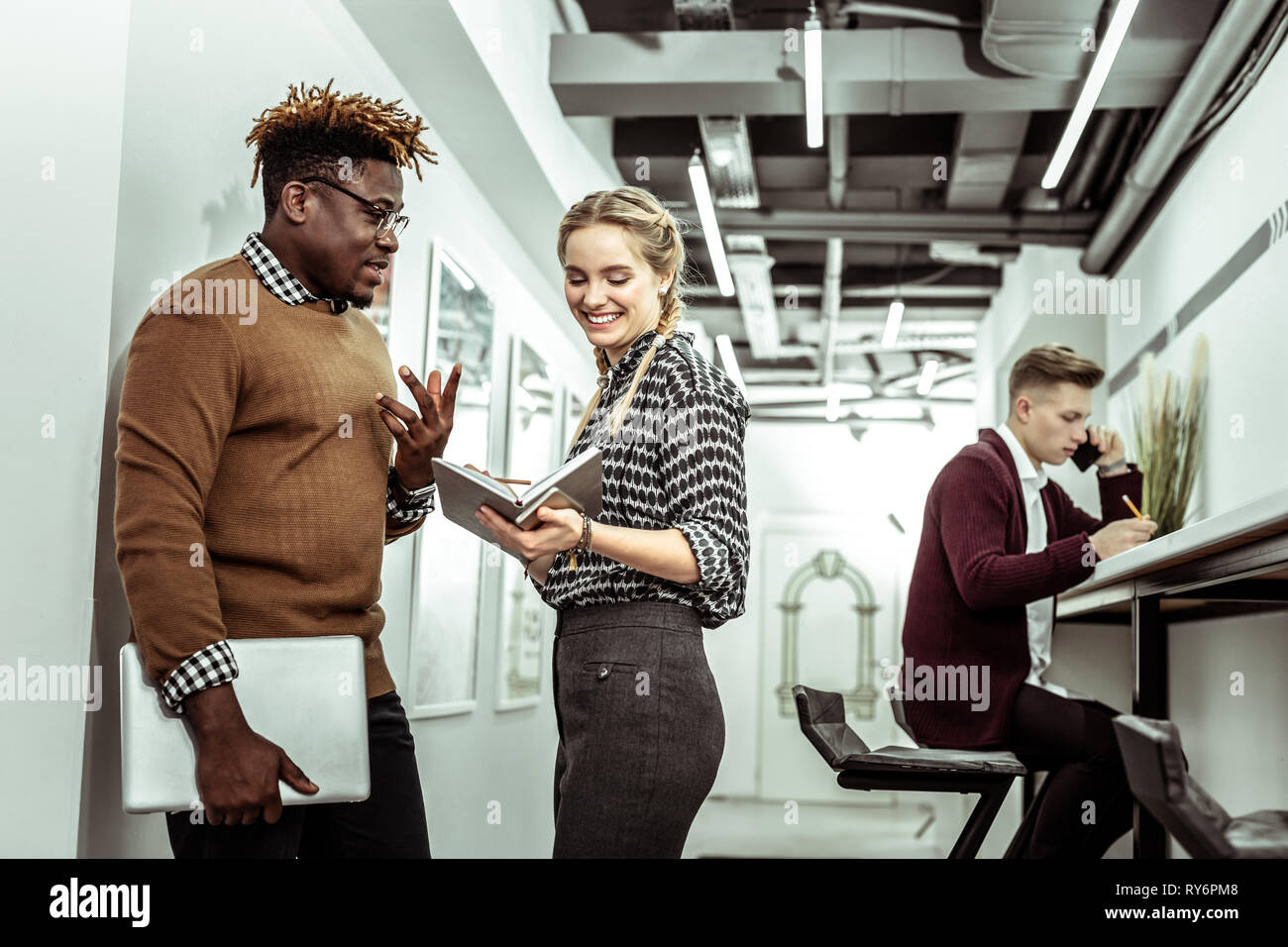 Cheerful young lady with wide smile standing with her colleague Stock ...