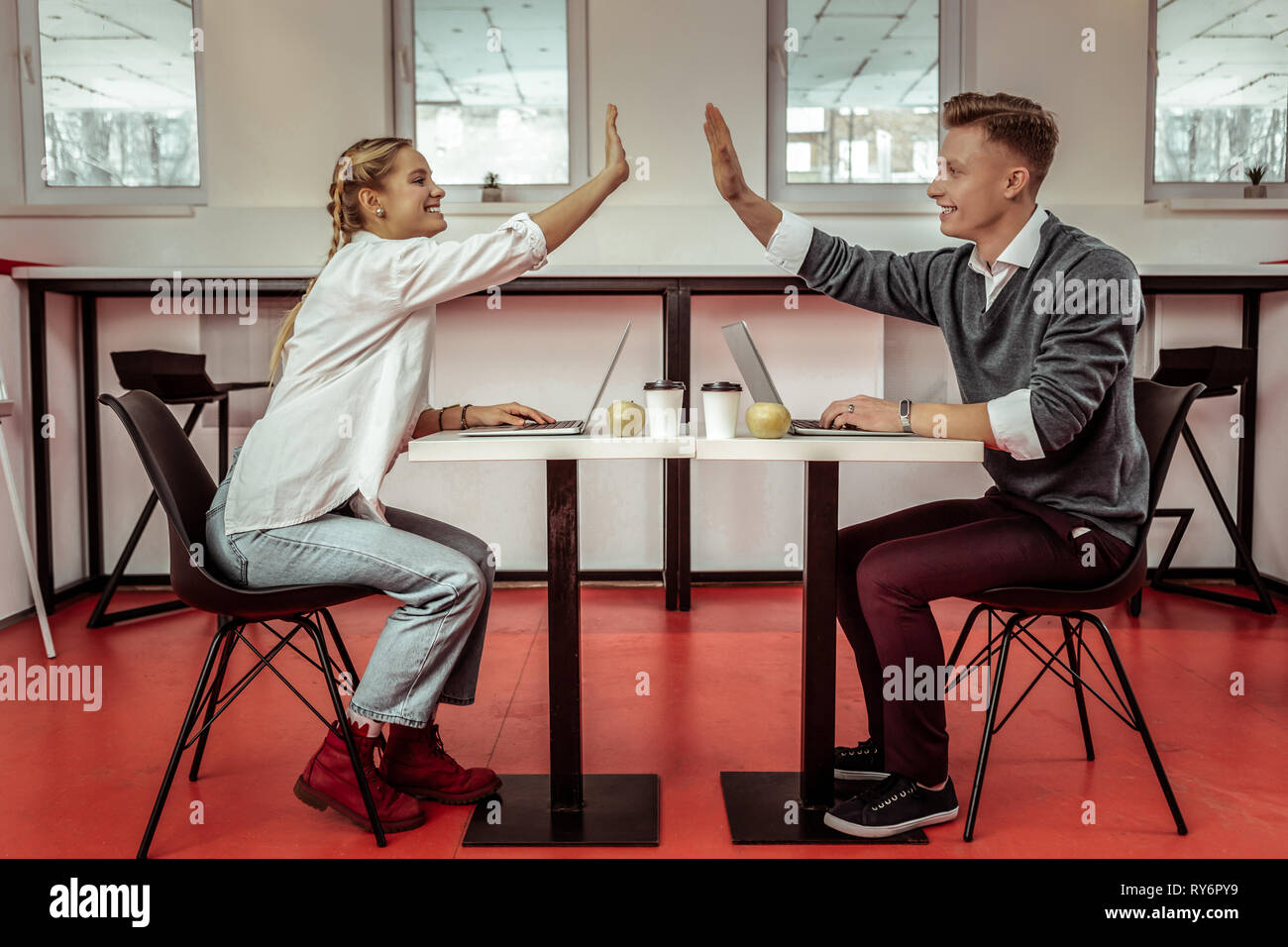 Smiling positive co-workers giving each other high five Stock Photo - Alamy