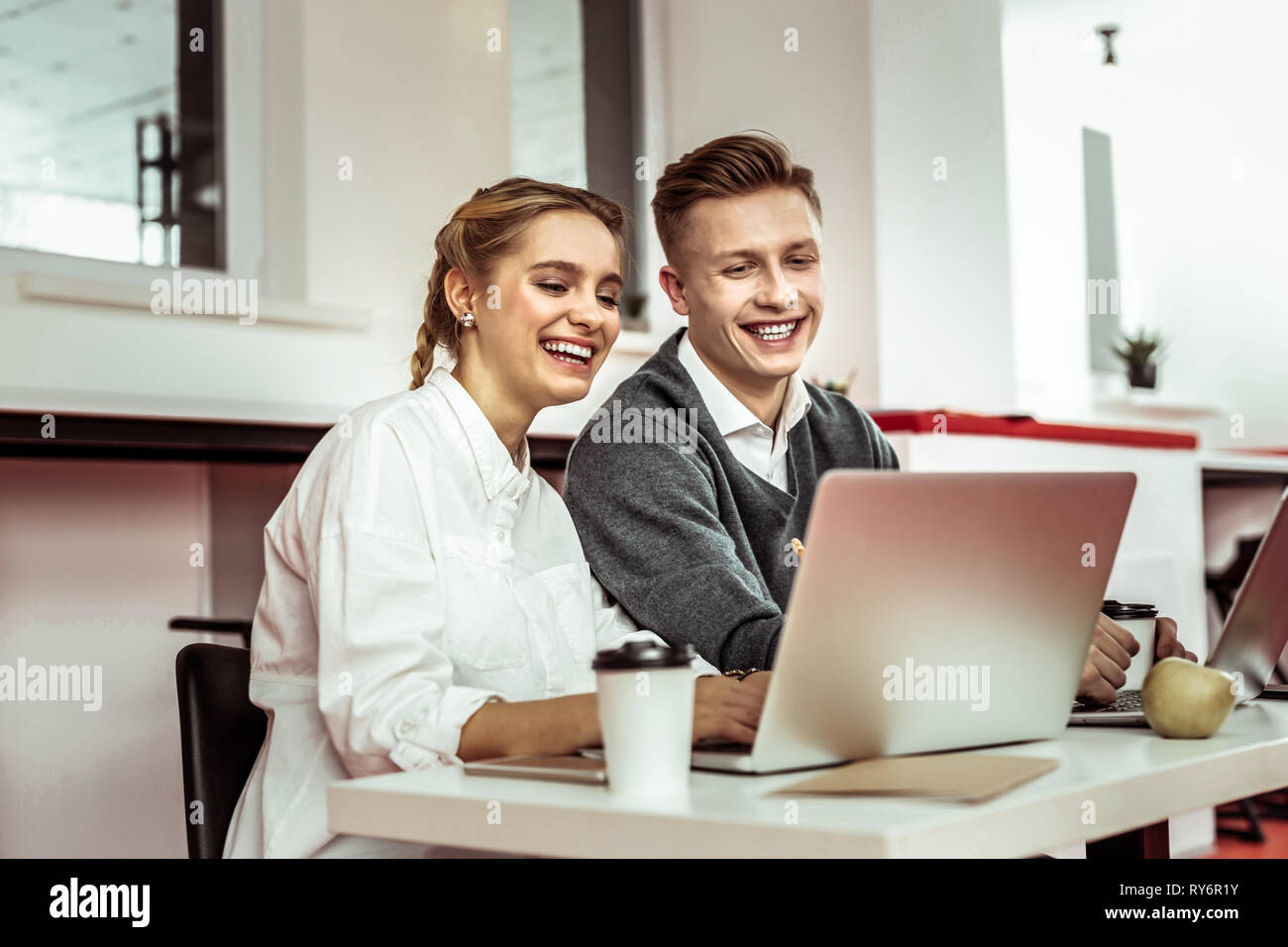 Laughing good-looking friends sitting close to each other Stock Photo ...