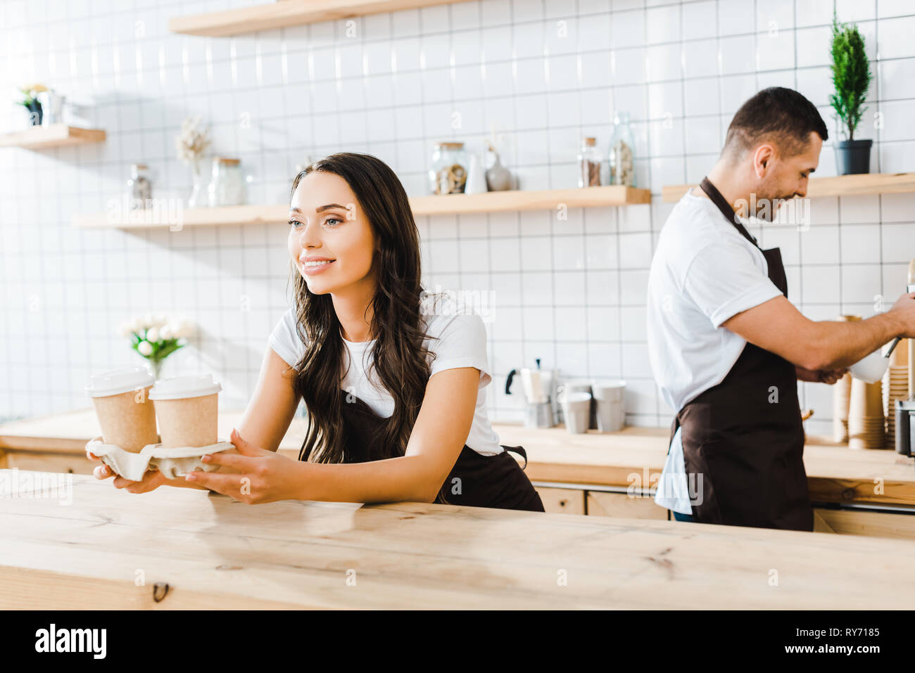 attractive brunette cashier standing behind bar counter and holding ...