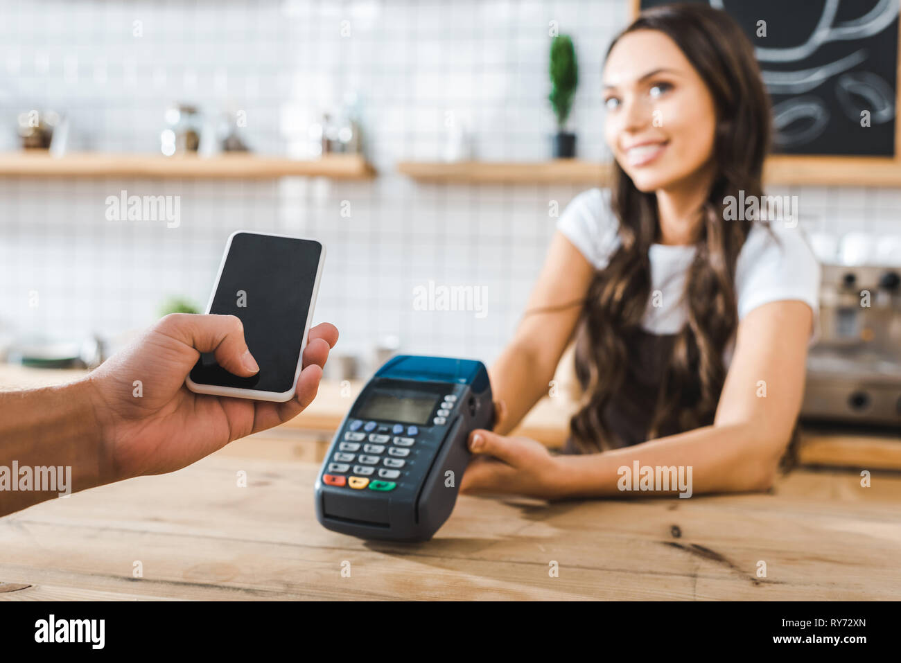 selective focus of male hand holding smartphone wile cashier standing ...